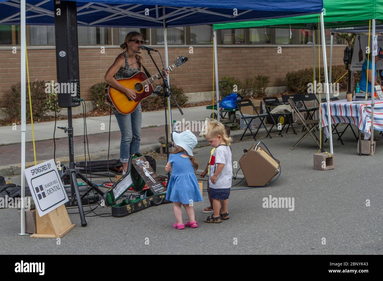 Pretty, blonde, female folk singer, playing guitar and singing at ...