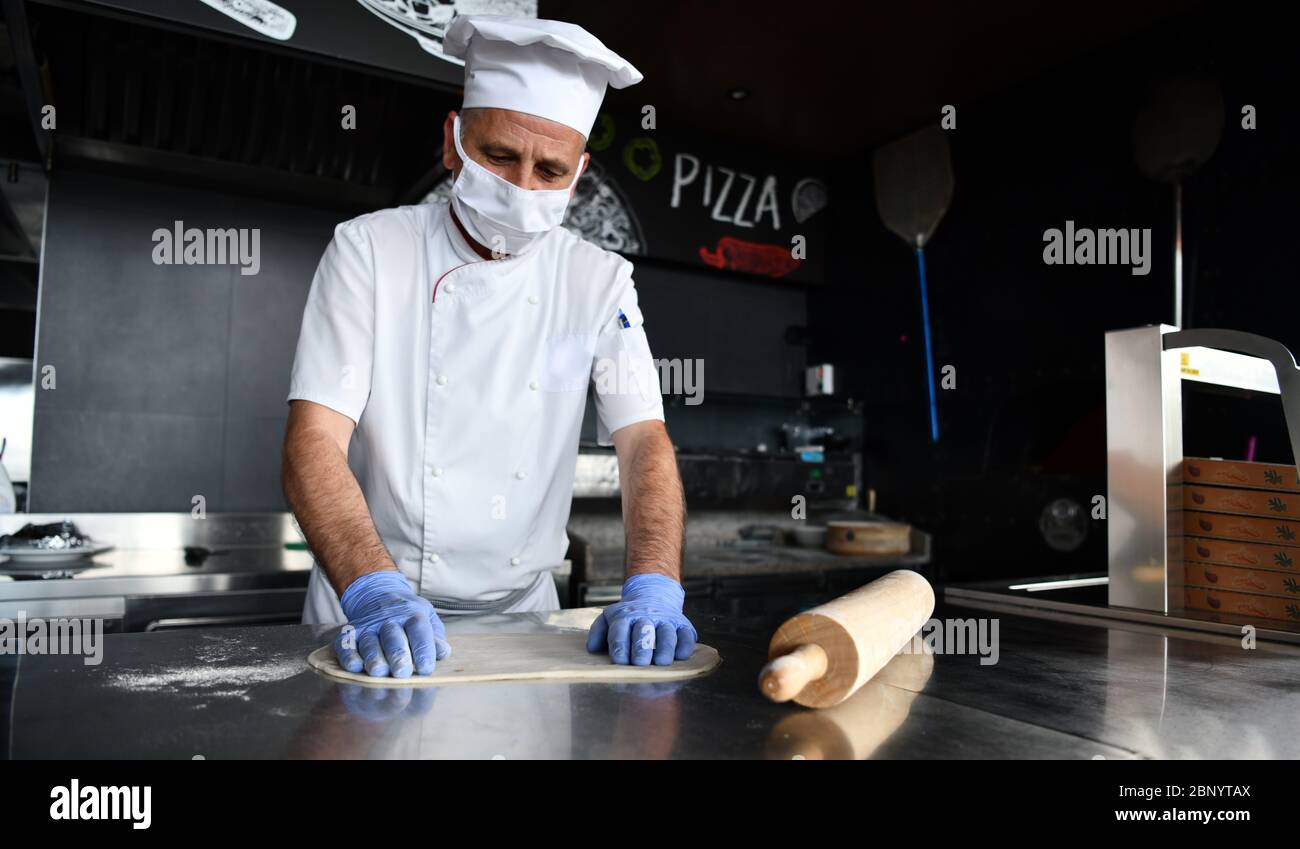 Skilled chef preparing traditional italian pizza in interior of modern ...
