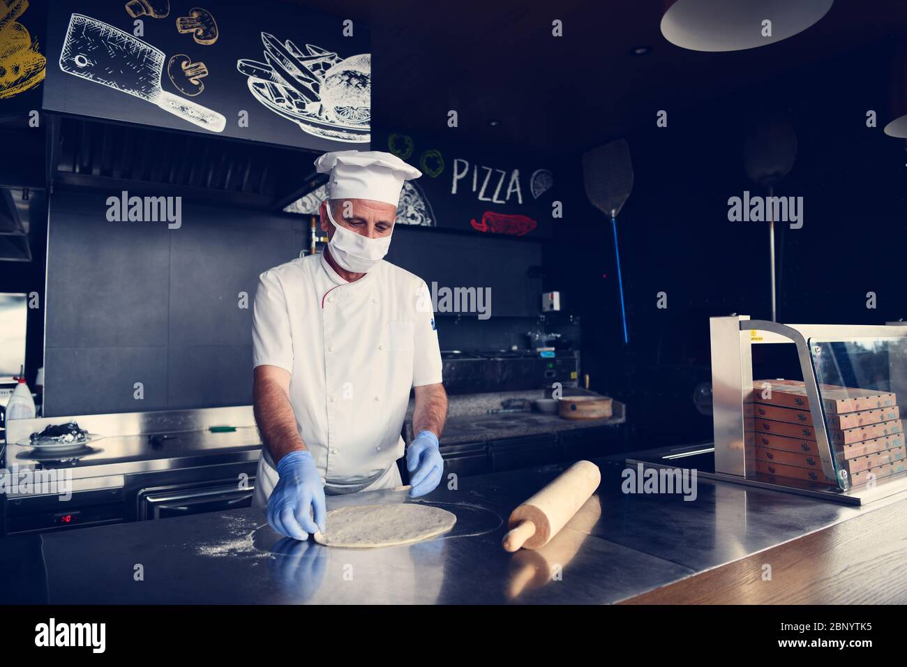 Skilled chef preparing traditional italian pizza in interior of modern ...