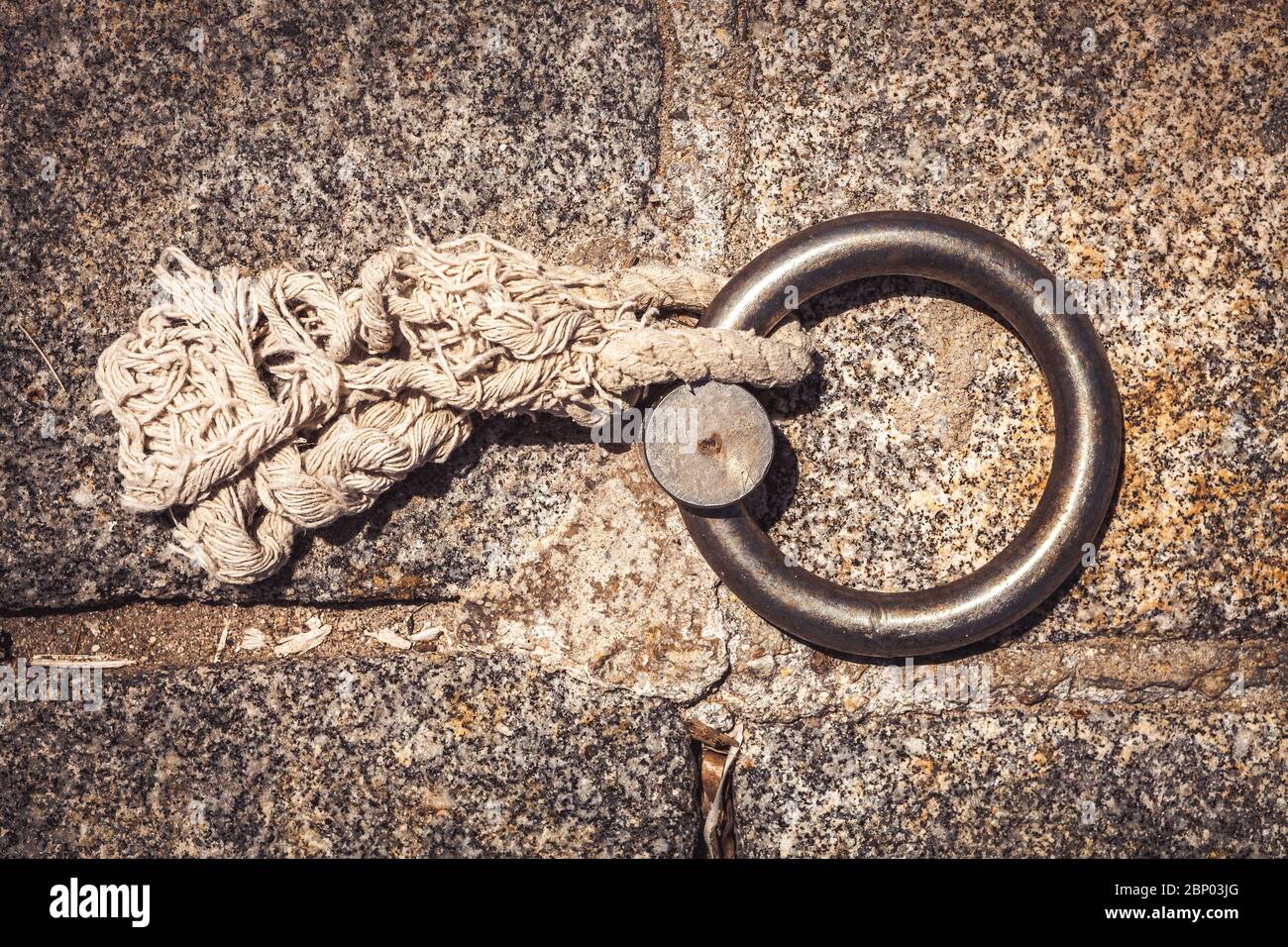 Steel ring and mooring lines in a seaport. Light colored hemp rope on ...