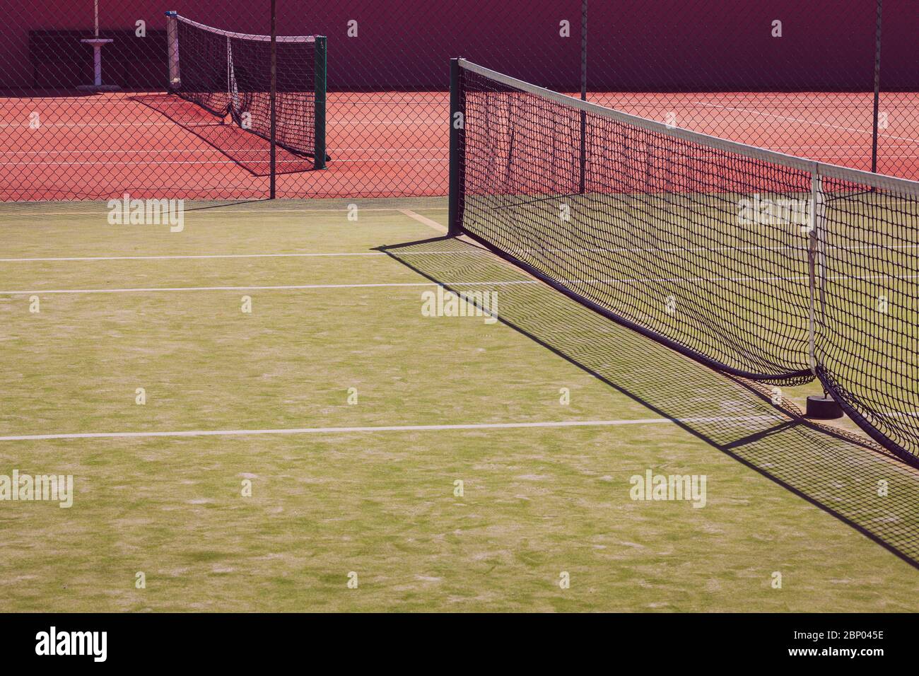 Tennis courts, green and red color. Tennis net in perspective. Nobody ...