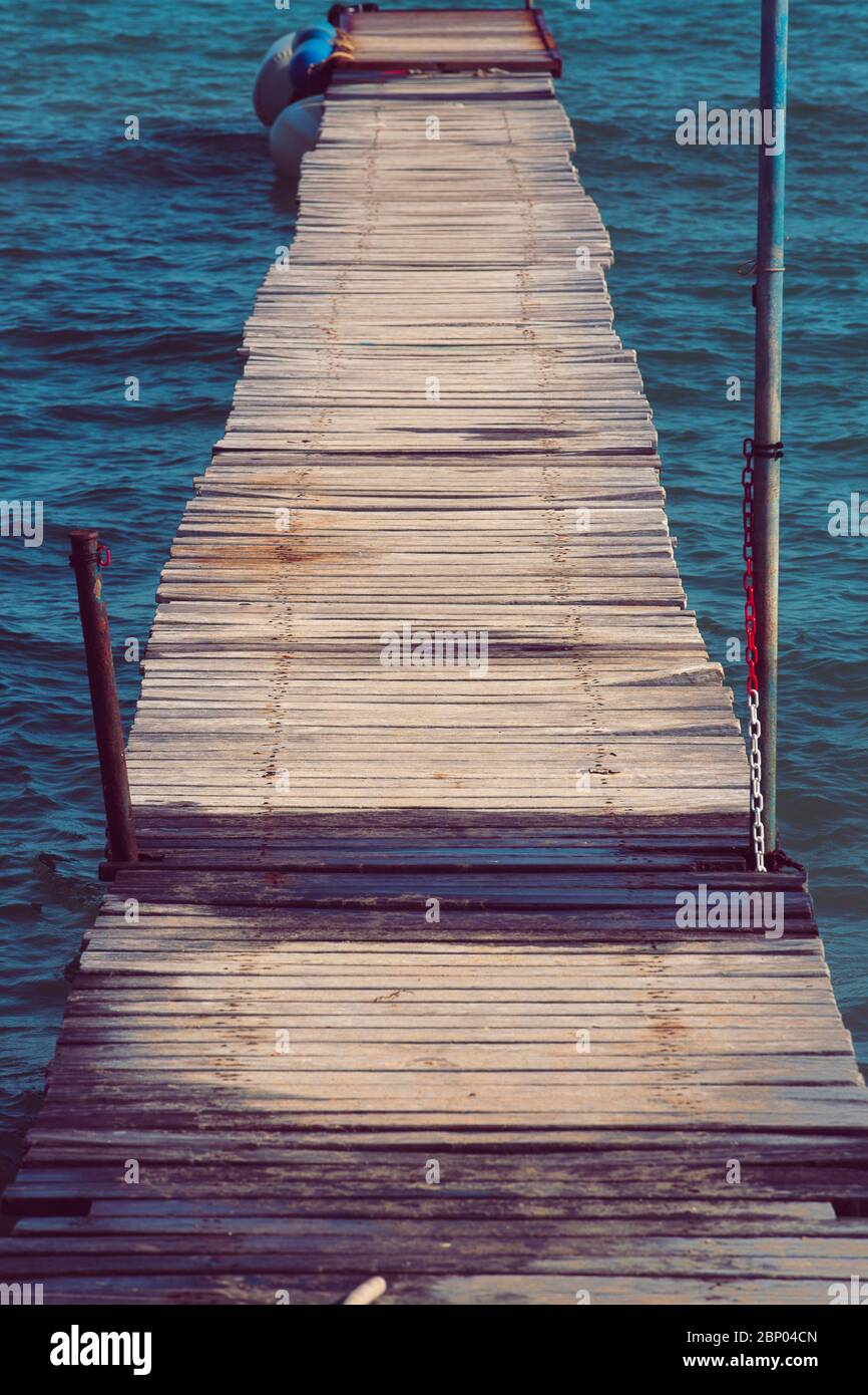 Antique wooden boardwalk over blue and azure sea. Small waves with calm ...