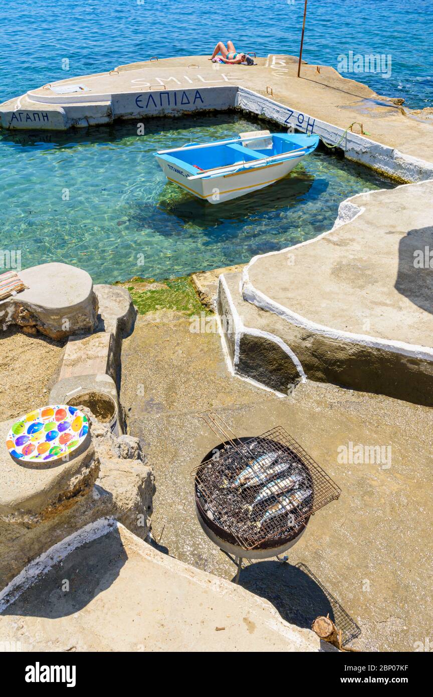 Picturesque small jetty, boat, sun bather and bbq grill - a seaside ...