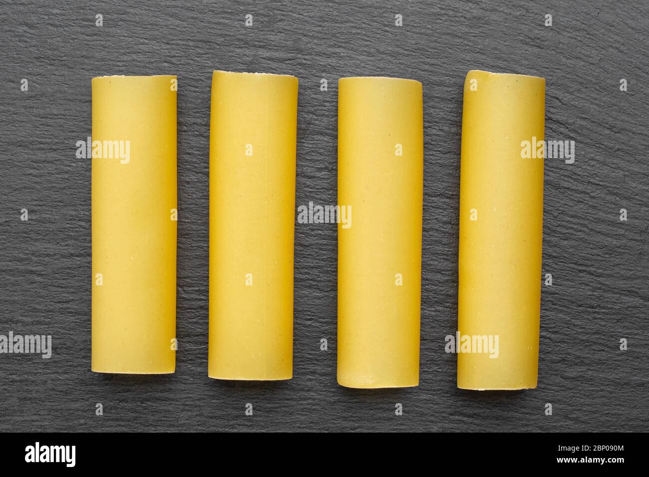 raw cannelloni pasta lie in a row on a black background. traditional ...