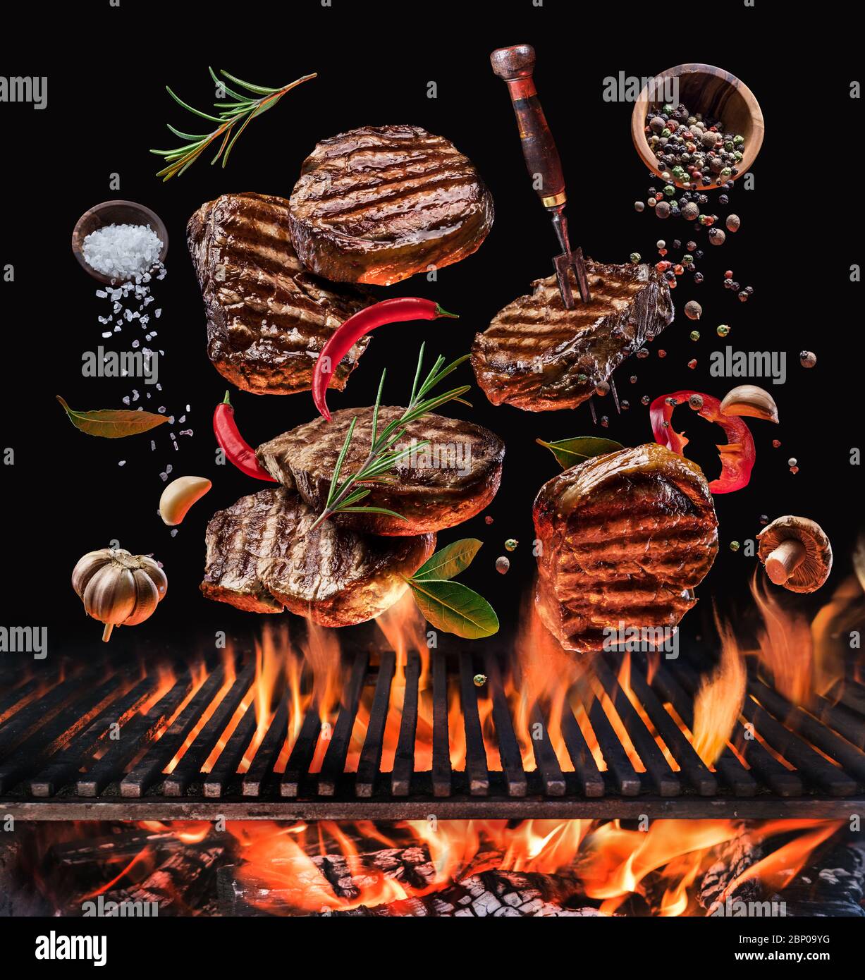 Grilled beef steaks and vegetables in motion falling down on open grill ...