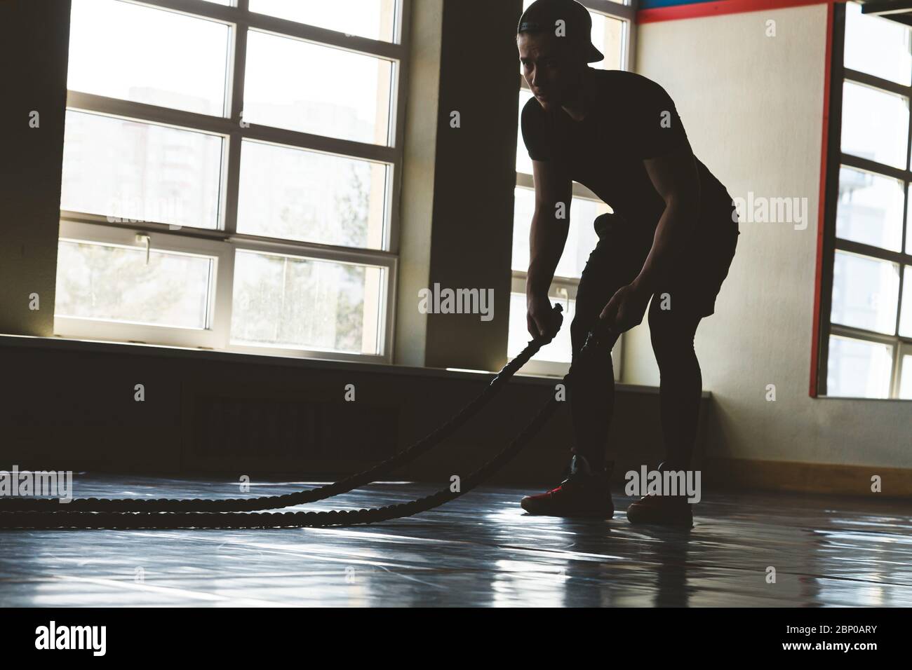 Exercise with ropes. The athlete is training in the gym. Silhouette ...