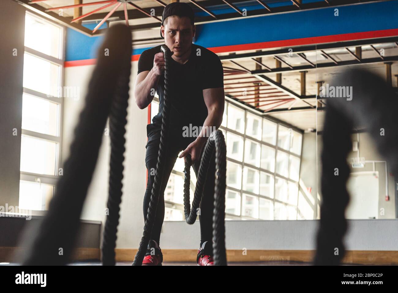 Muscular man in the gym with ropes doing exercises Stock Photo - Alamy