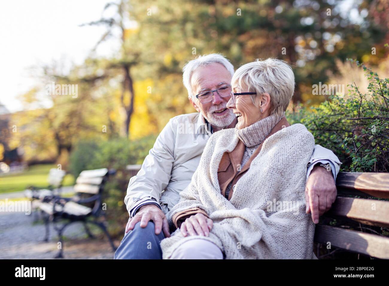 Old man and woman sitting on bench and smile Stock Photo - Alamy