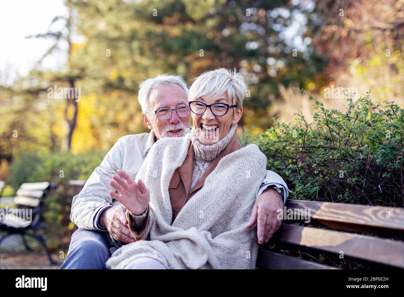 Old man and woman sitting on bench and smile Stock Photo - Alamy