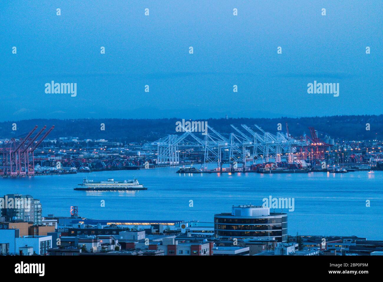 big ferry moving into downtown Seattle with industrail port background ...