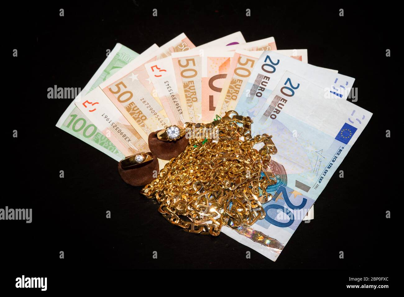 Money and gold jewellery against a black background Stock Photo - Alamy