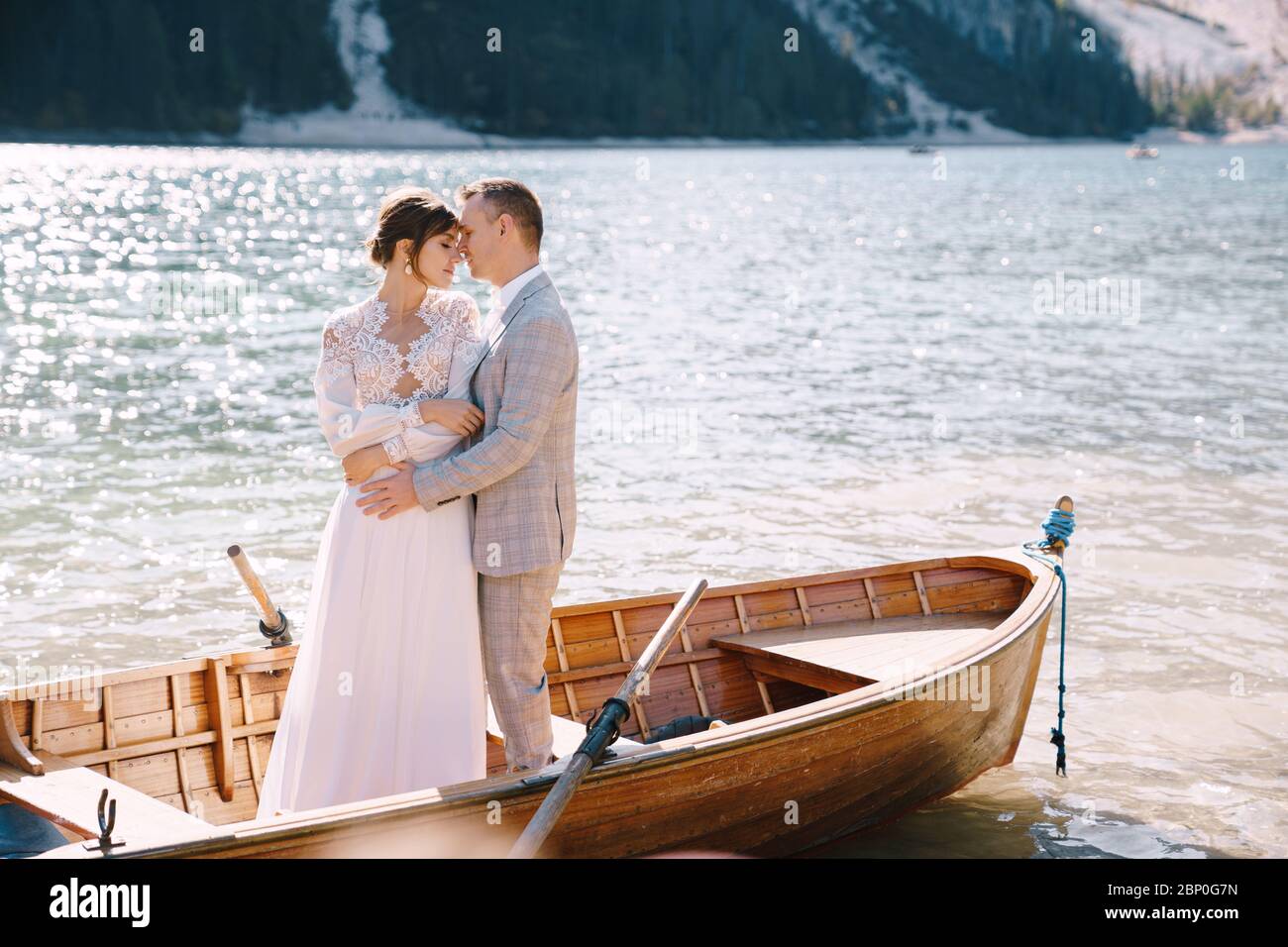 Bride and groom sailing in wooden boat, with oars at Lago di Braies ...