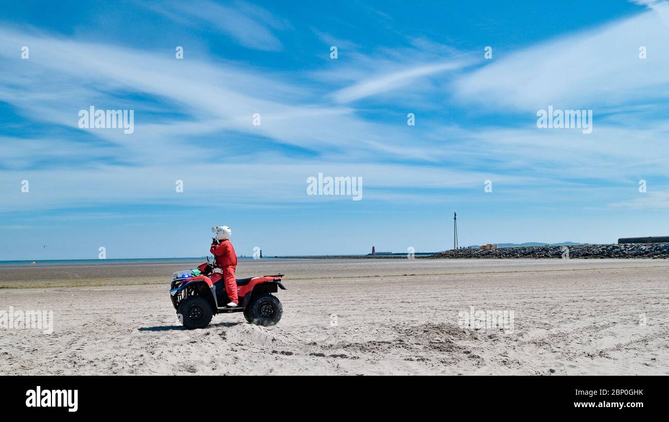 Lifeguard patrols on a quad, checks and looks at the beach, Ireland ...