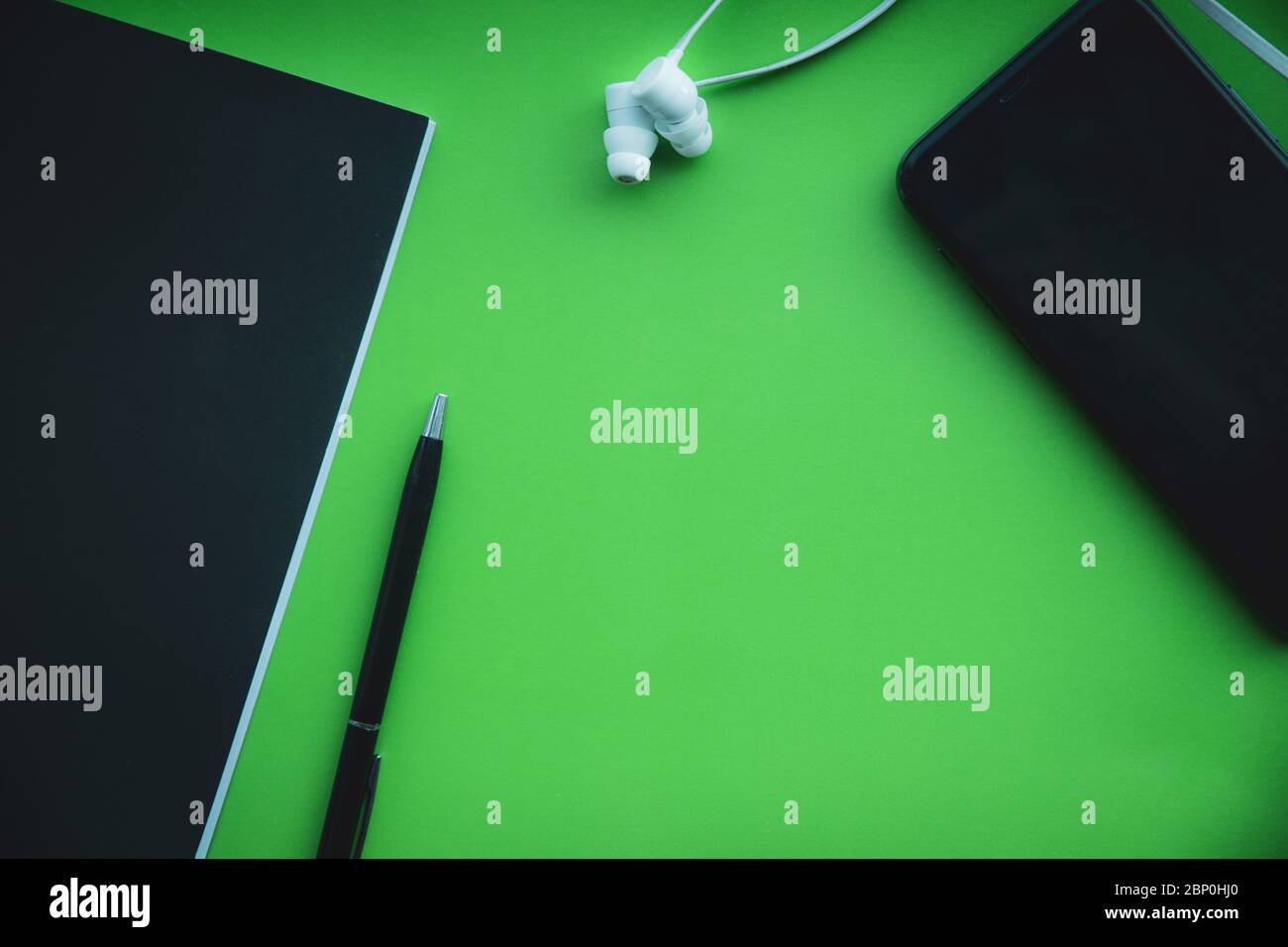 Black screen of mobile phone device, notepad, pen and white headphones ...