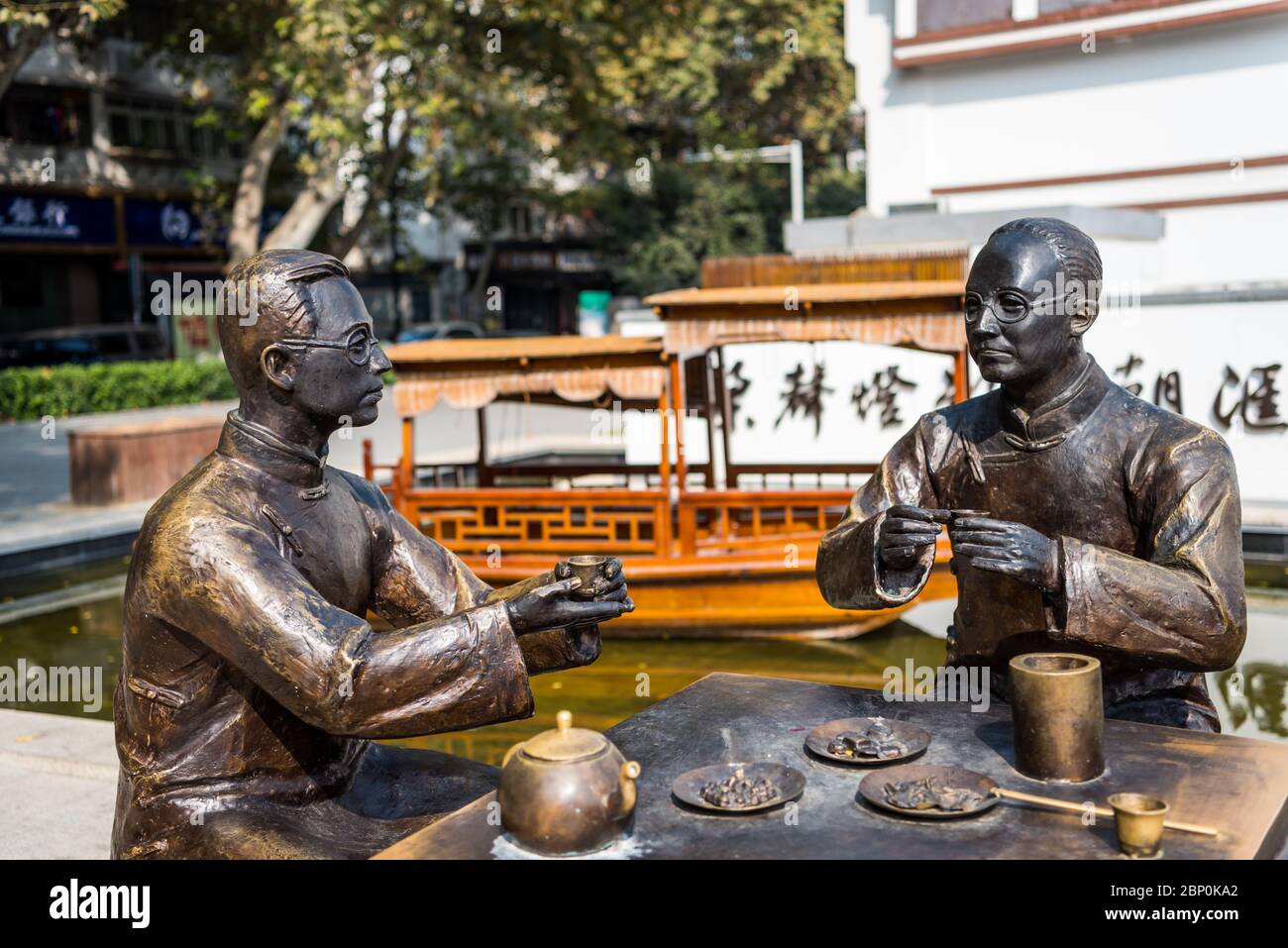 Statue of two Chinese young man drinking tea together on the bank of ...