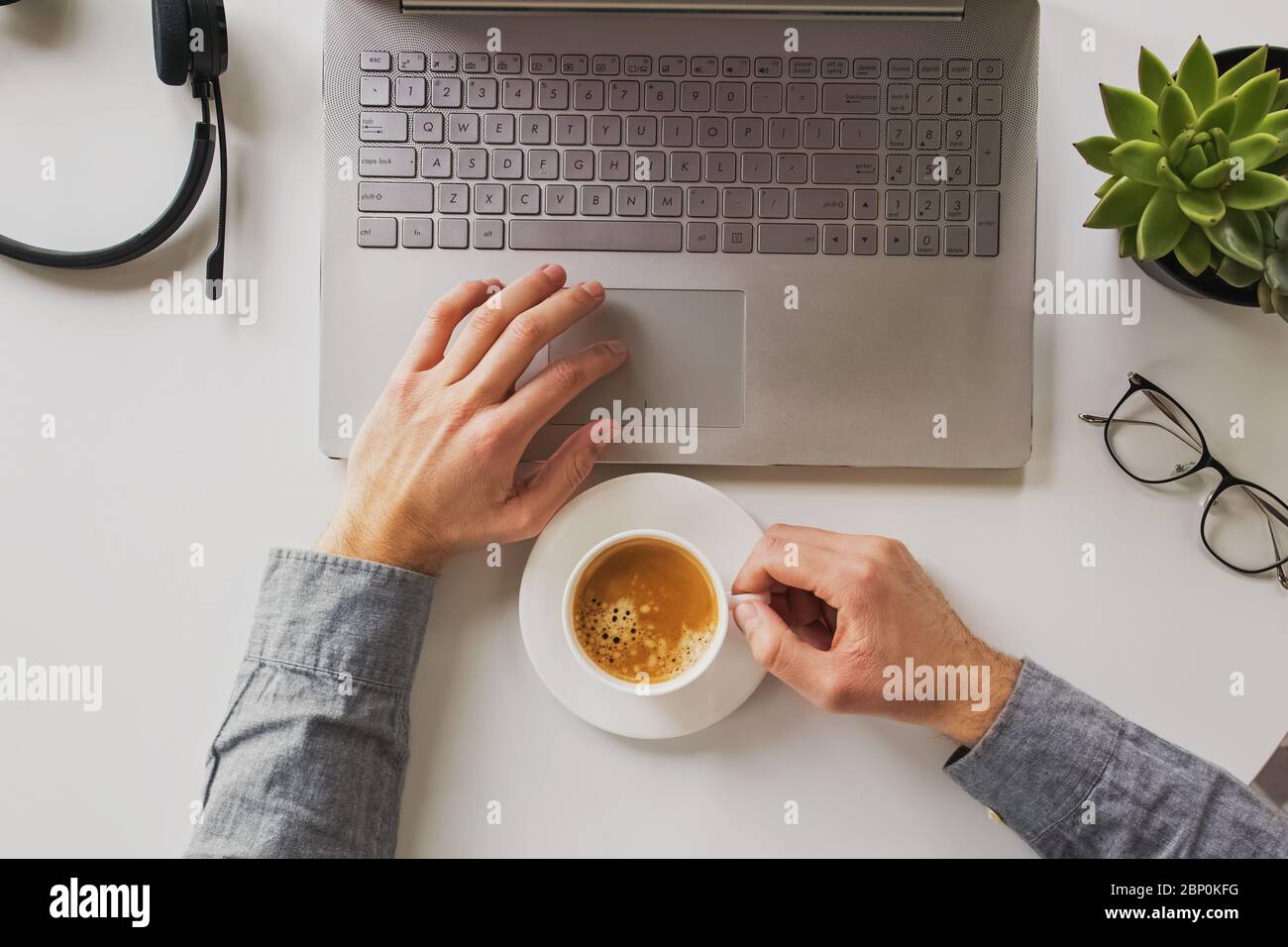 Man working on laptop and drinking coffee Stock Photo - Alamy
