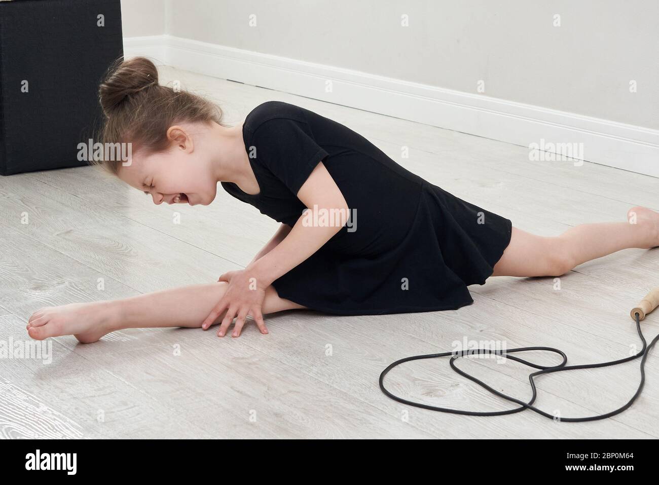 Little girl doing split and gymnastics exercise at home feeling much ...
