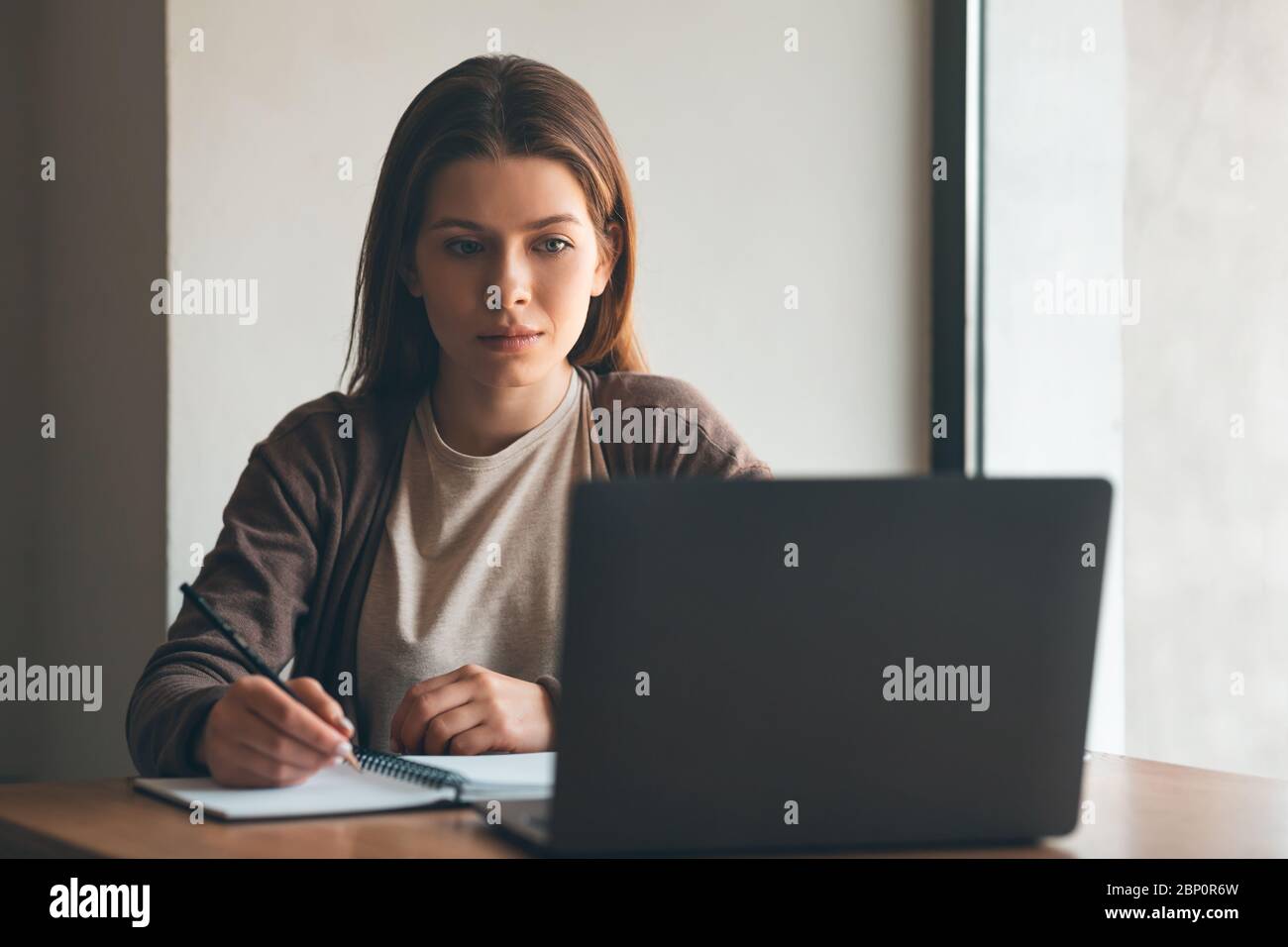Concentrated young girl writing notes while listening free webinar ...