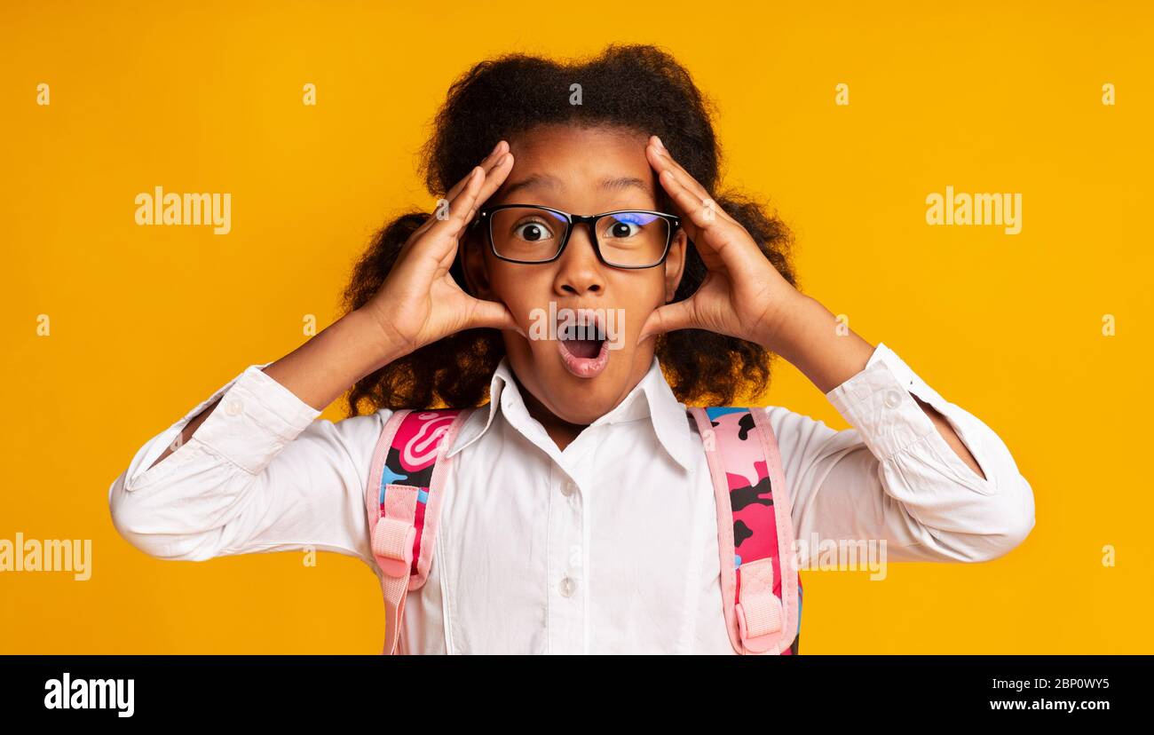 Shocked African Schoolgirl Cupping Head Standing On Yellow Studio ...