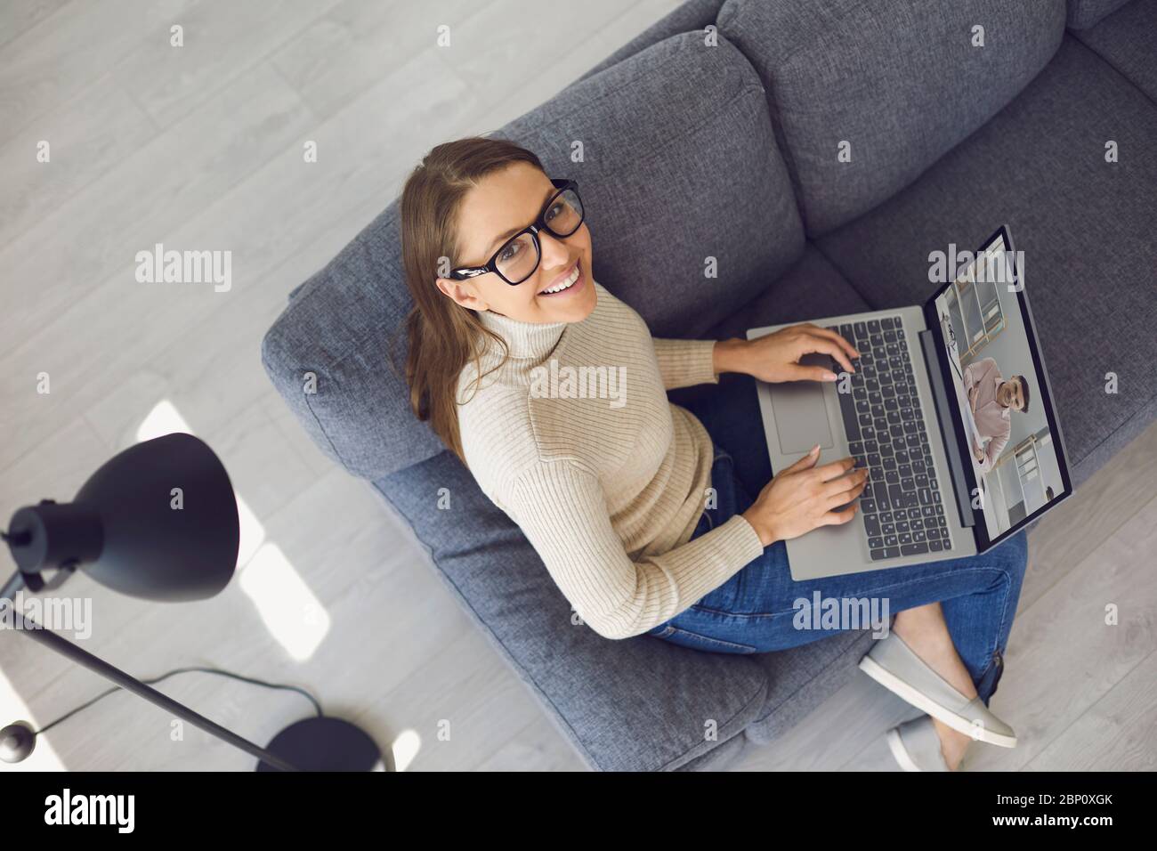 Online work at home. A smiling woman with a laptop looks at the camera ...