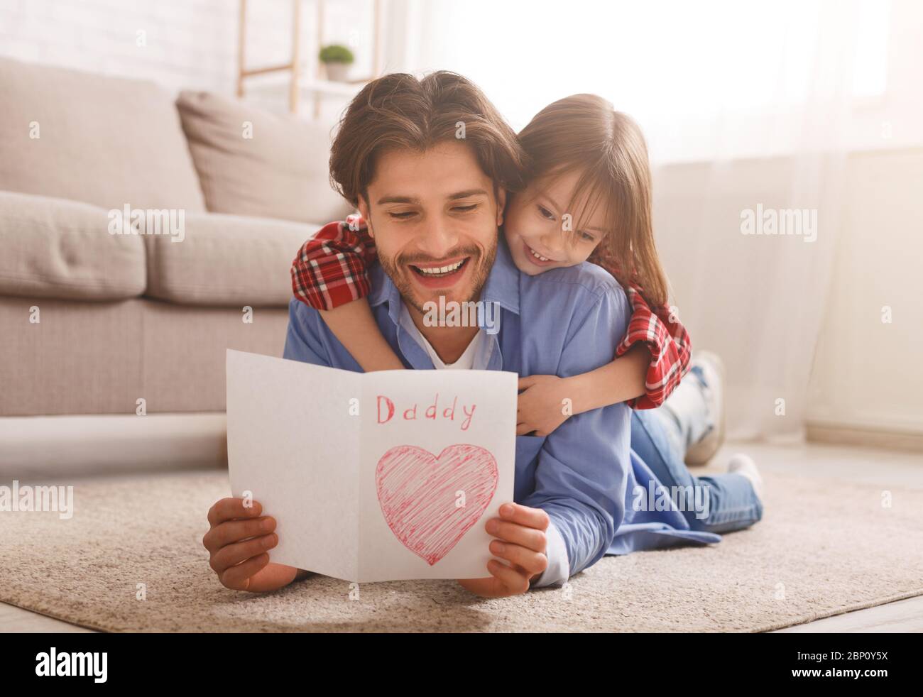 Happy dad reading greeting card while bonding with daughter Stock Photo ...