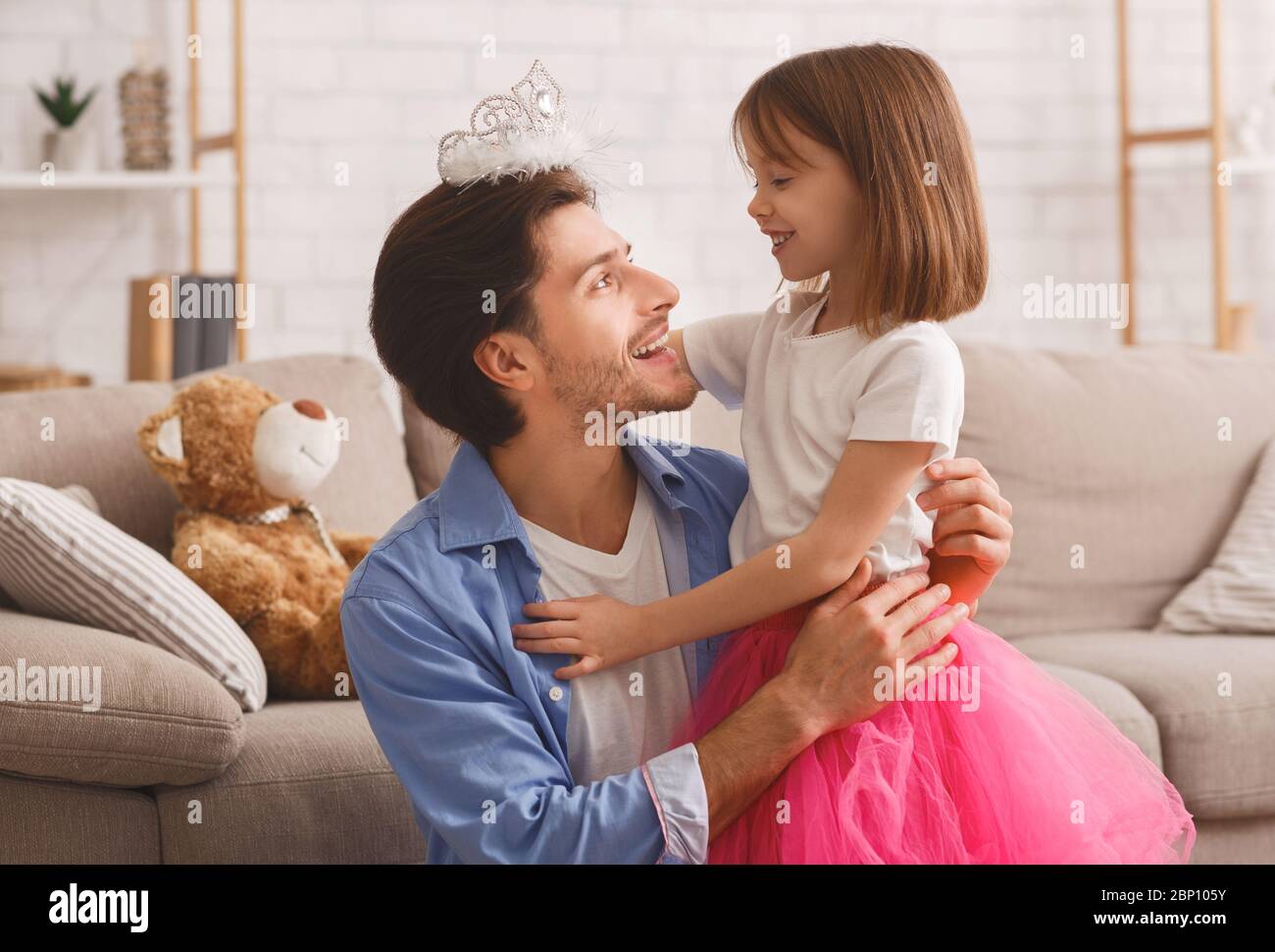 Small pretty girl putting crown on her dad Stock Photo - Alamy