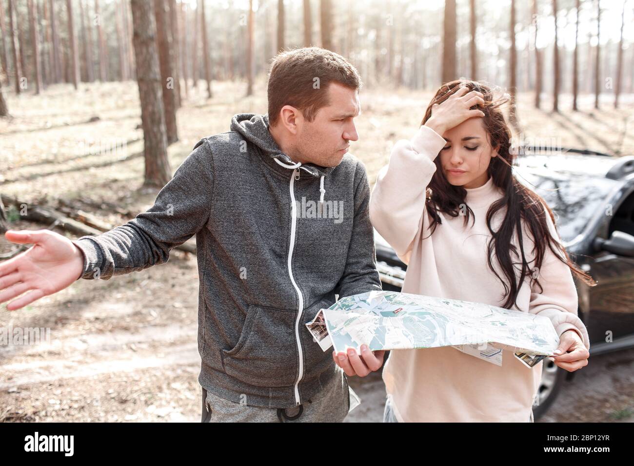 Man and woman lost in the forest. They are standing with a map and do ...
