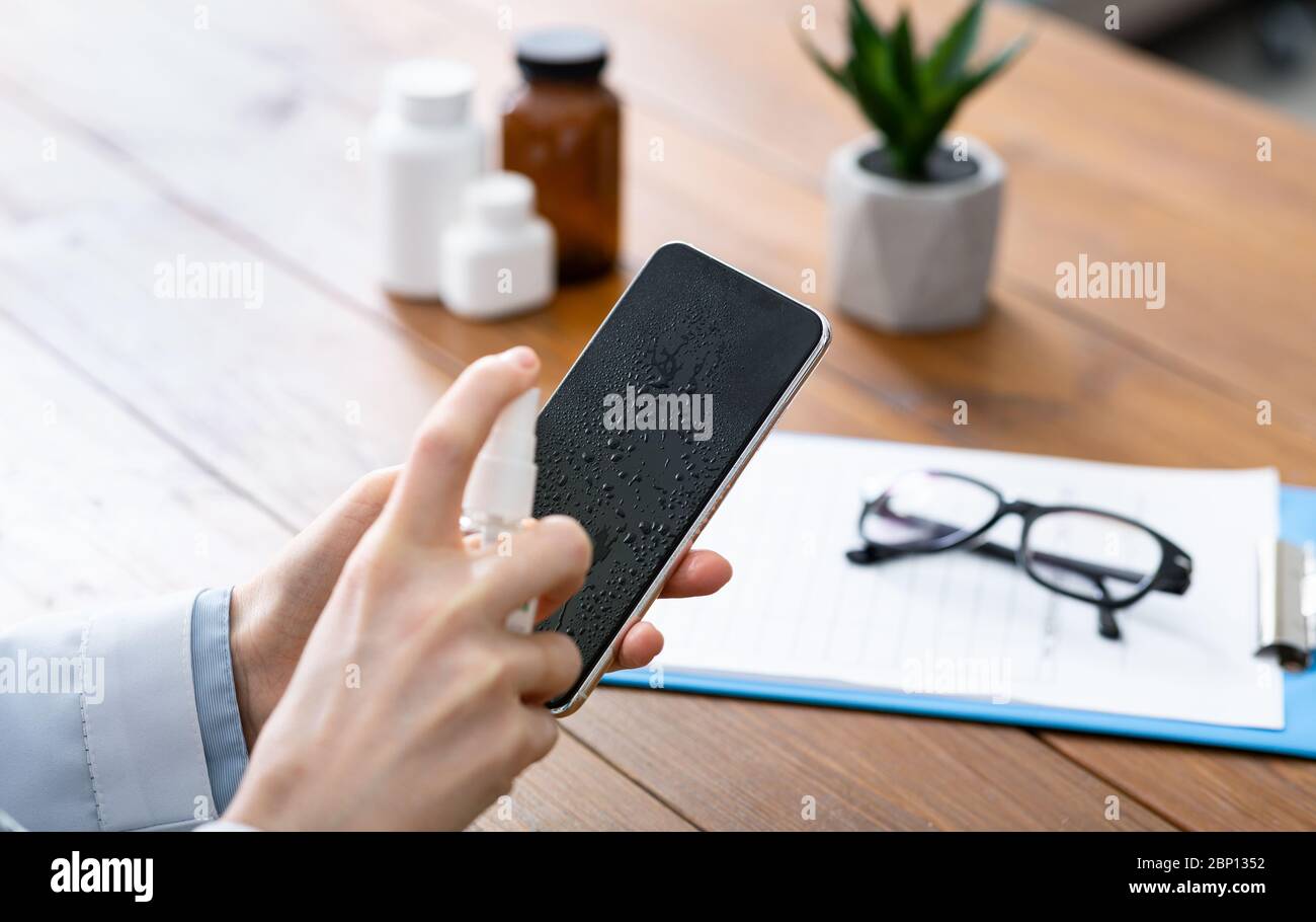 Fight off viruses and germs. Women hands disinfect phone with ...