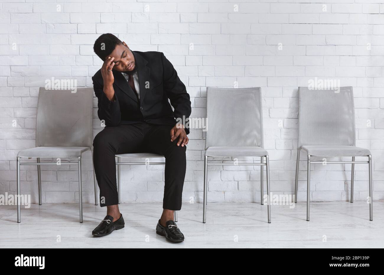 Pensive black guy in office wear waiting for job interview in company ...