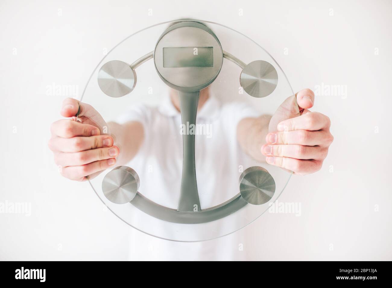 Young man isolated over white background. Guy hold transparent weight ...
