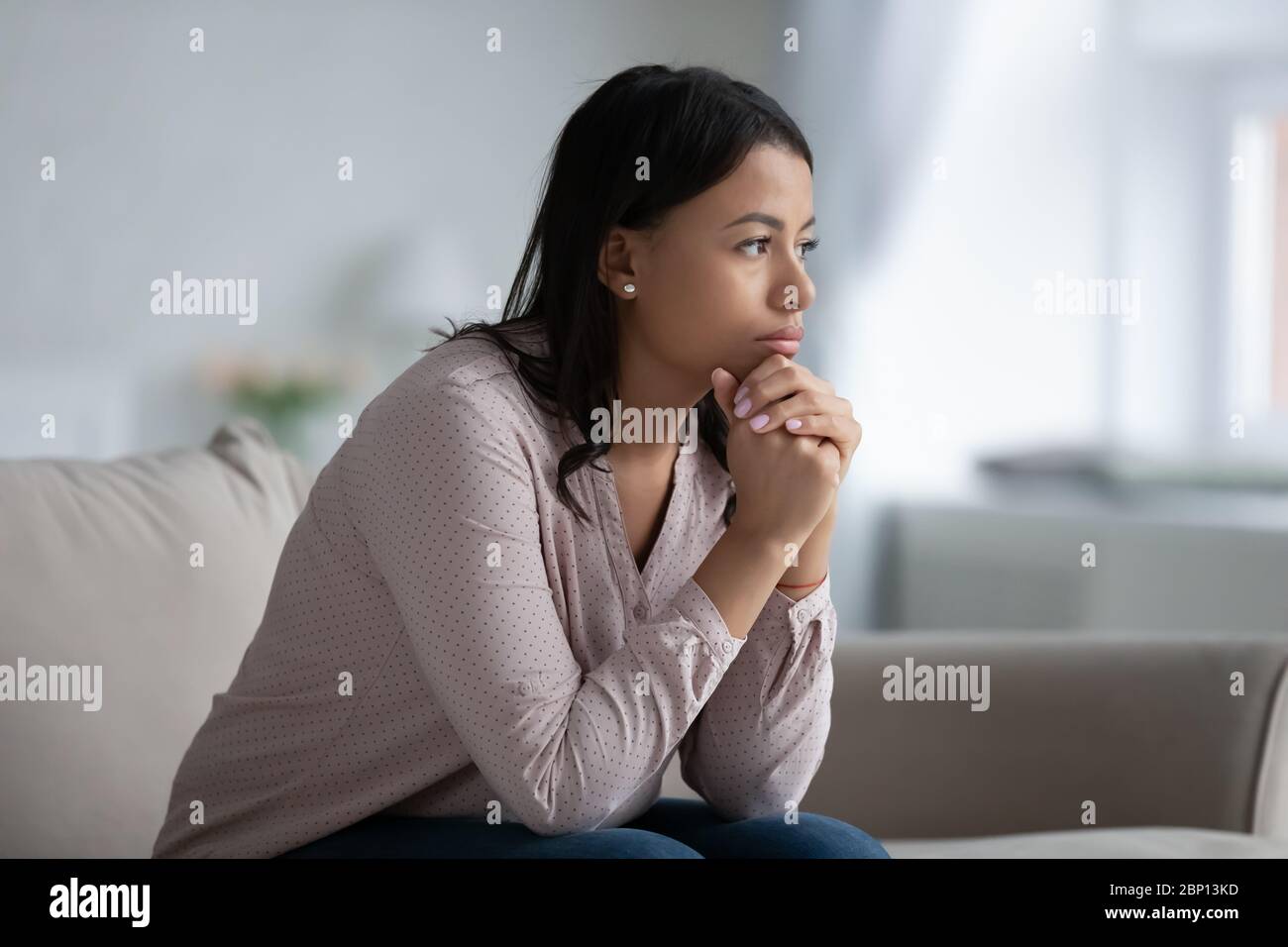 Sad African woman sit on sofa thinking of life troubles Stock Photo - Alamy