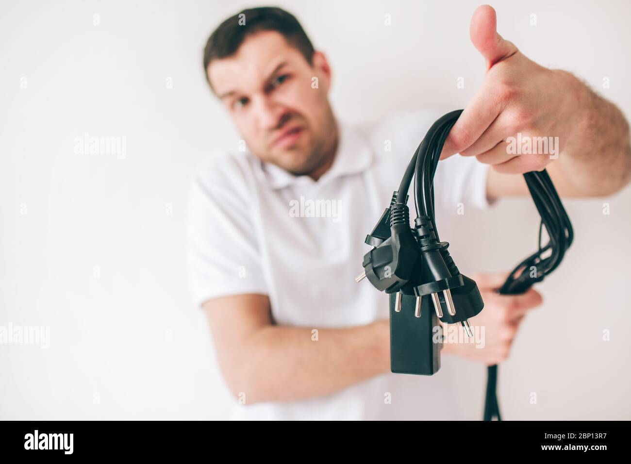 Young man isolated over white background. Electrician guy with cords ...