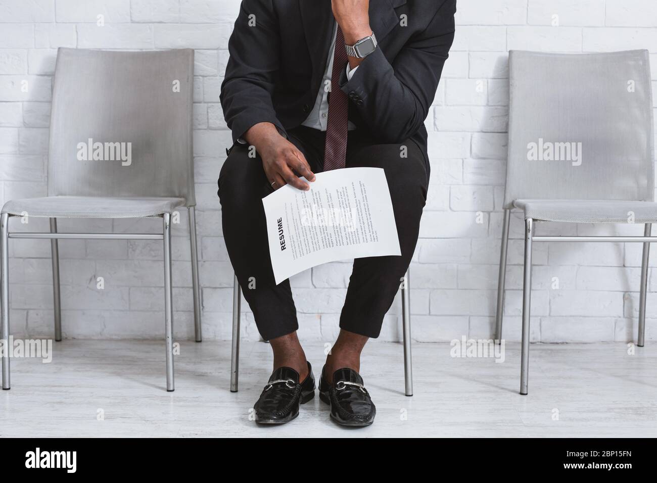 Closeup view of black guy in office suit with resume waiting for job ...