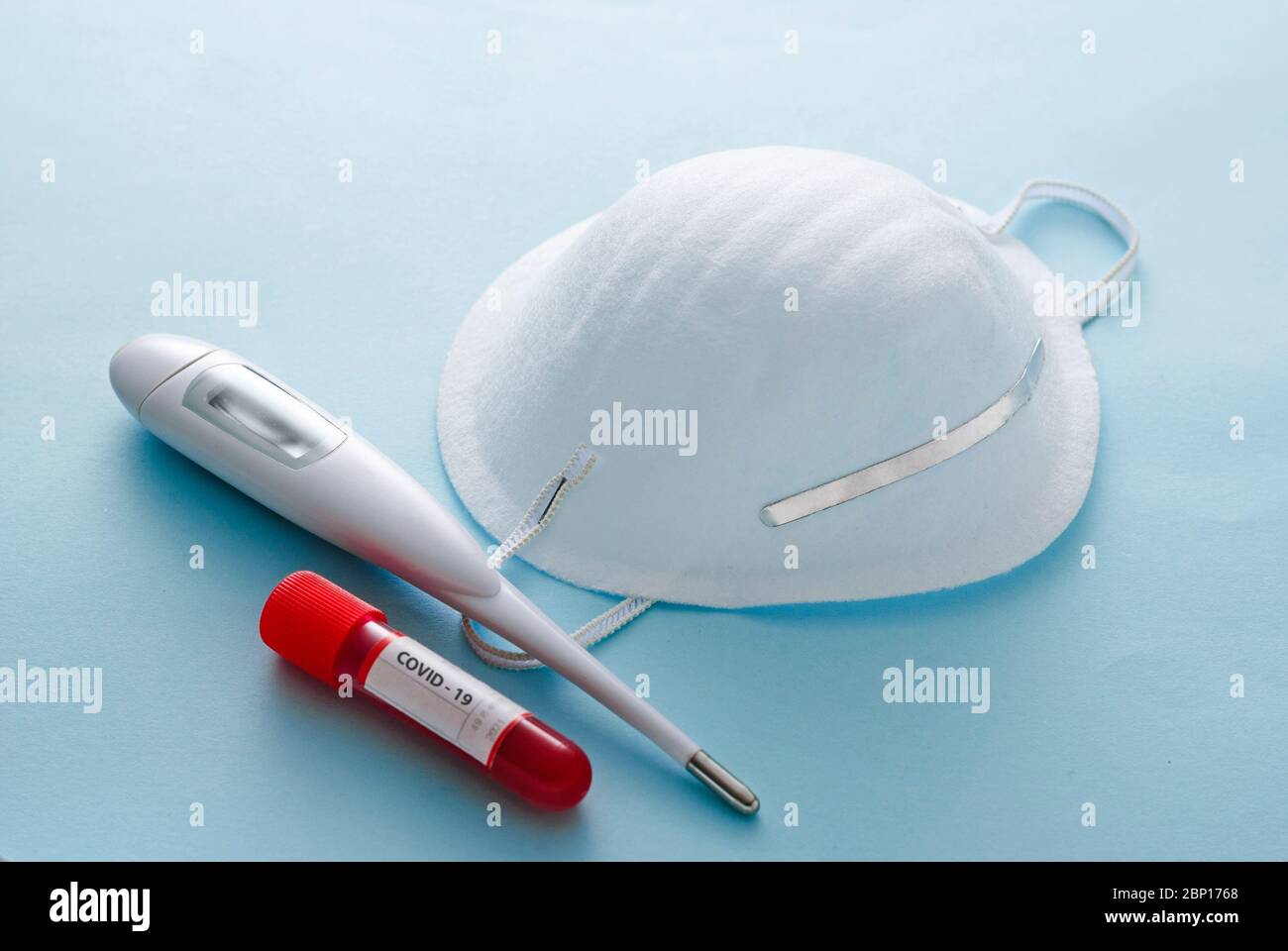 Face mask with clinical thermometer and blood sample in a test tube ...