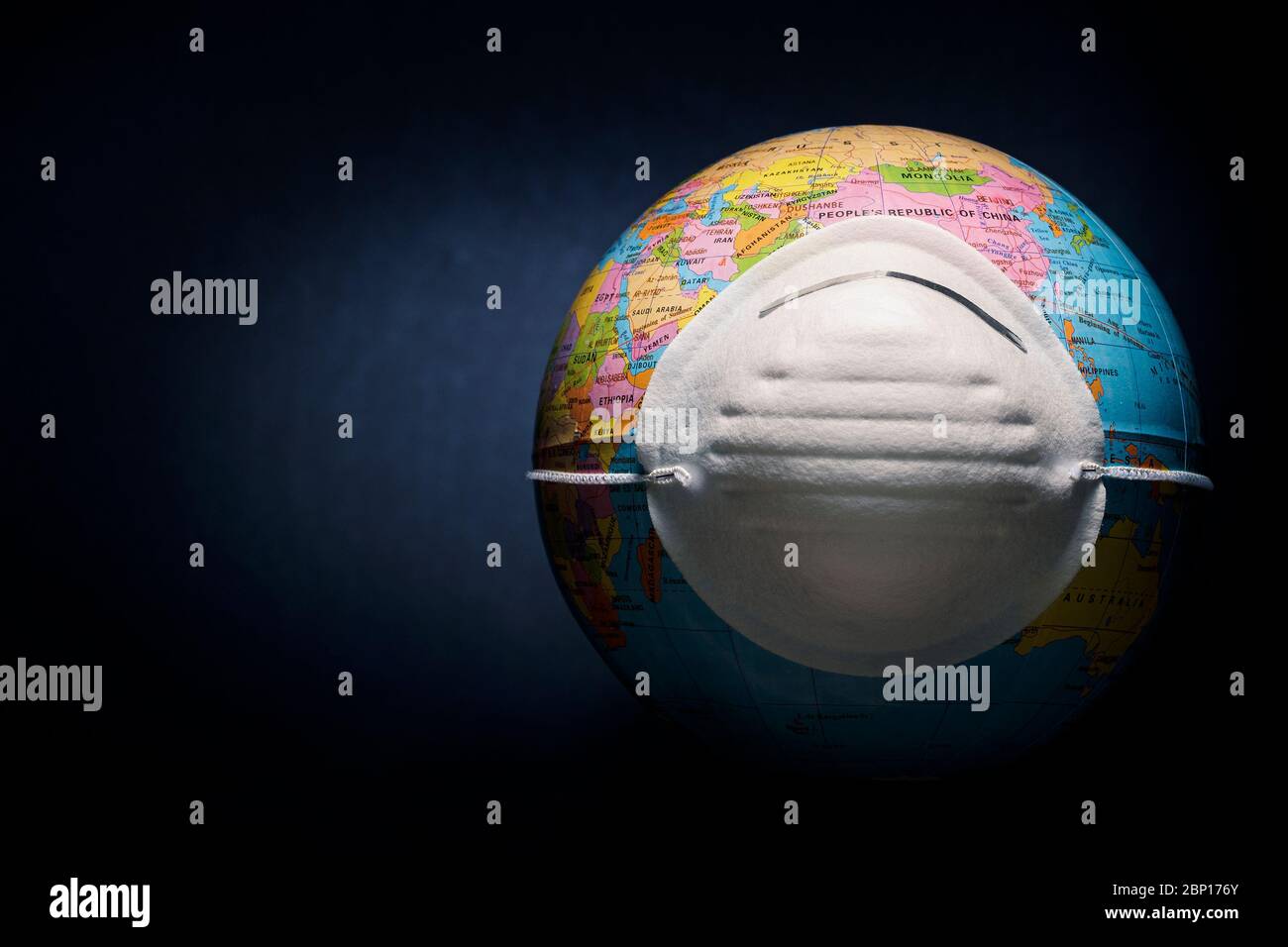 World globe wearing a protective face mask in side view on a black ...