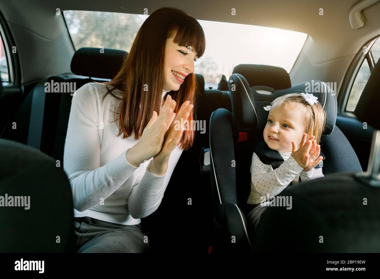 Pretty laughing woman, young mother sitting in a car, having having fun ...