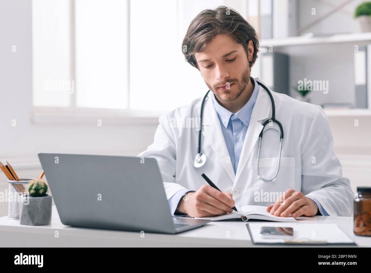 Male medical doctor making timetable for patients at office Stock Photo ...