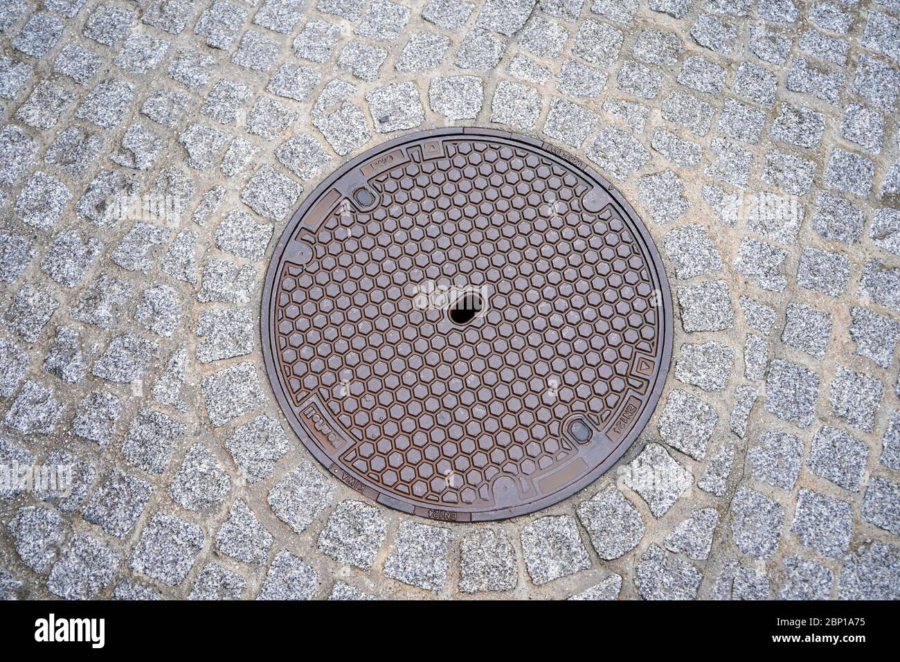 Sewer manhole in the middle of paving stones in Vaduz, the capital of ...