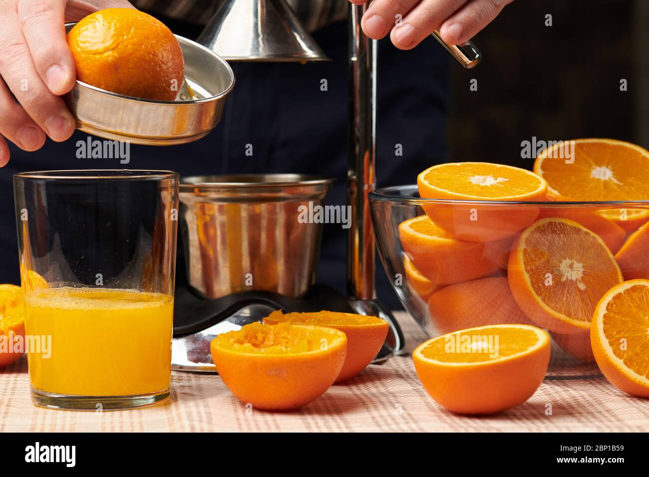 Squeezing an orange with a manual press, close view, making a glass of ...