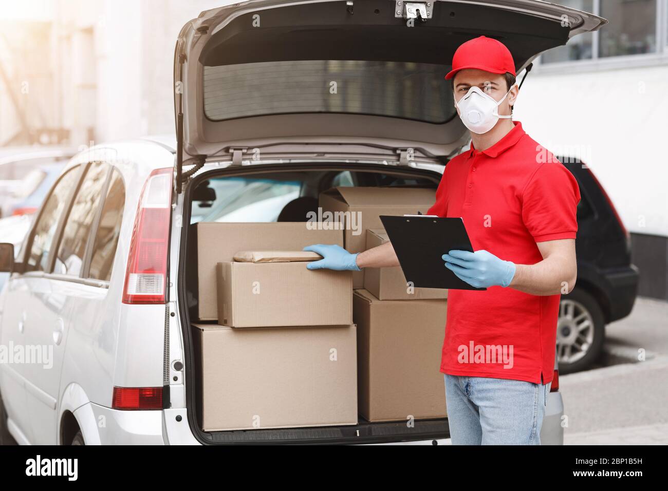 Delivery man is checking parcel. Courier with tablet, put his hand on ...