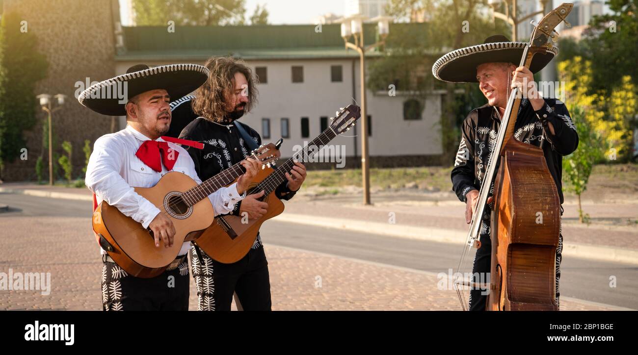 Mexican musicians play musical instruments in the city. City street in ...