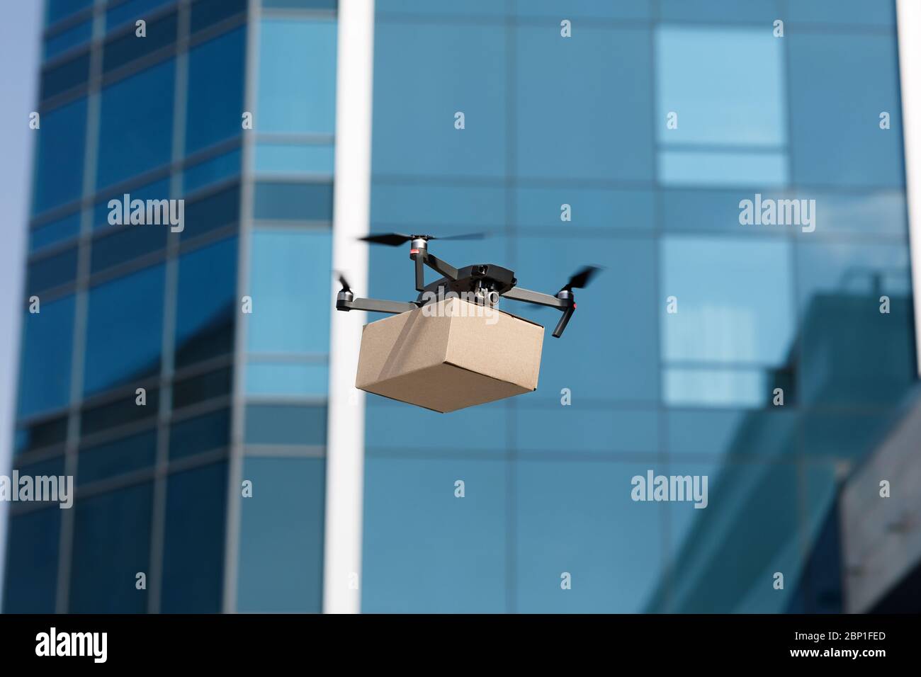 Drone quadcopter carrying a package through the city Stock Photo - Alamy