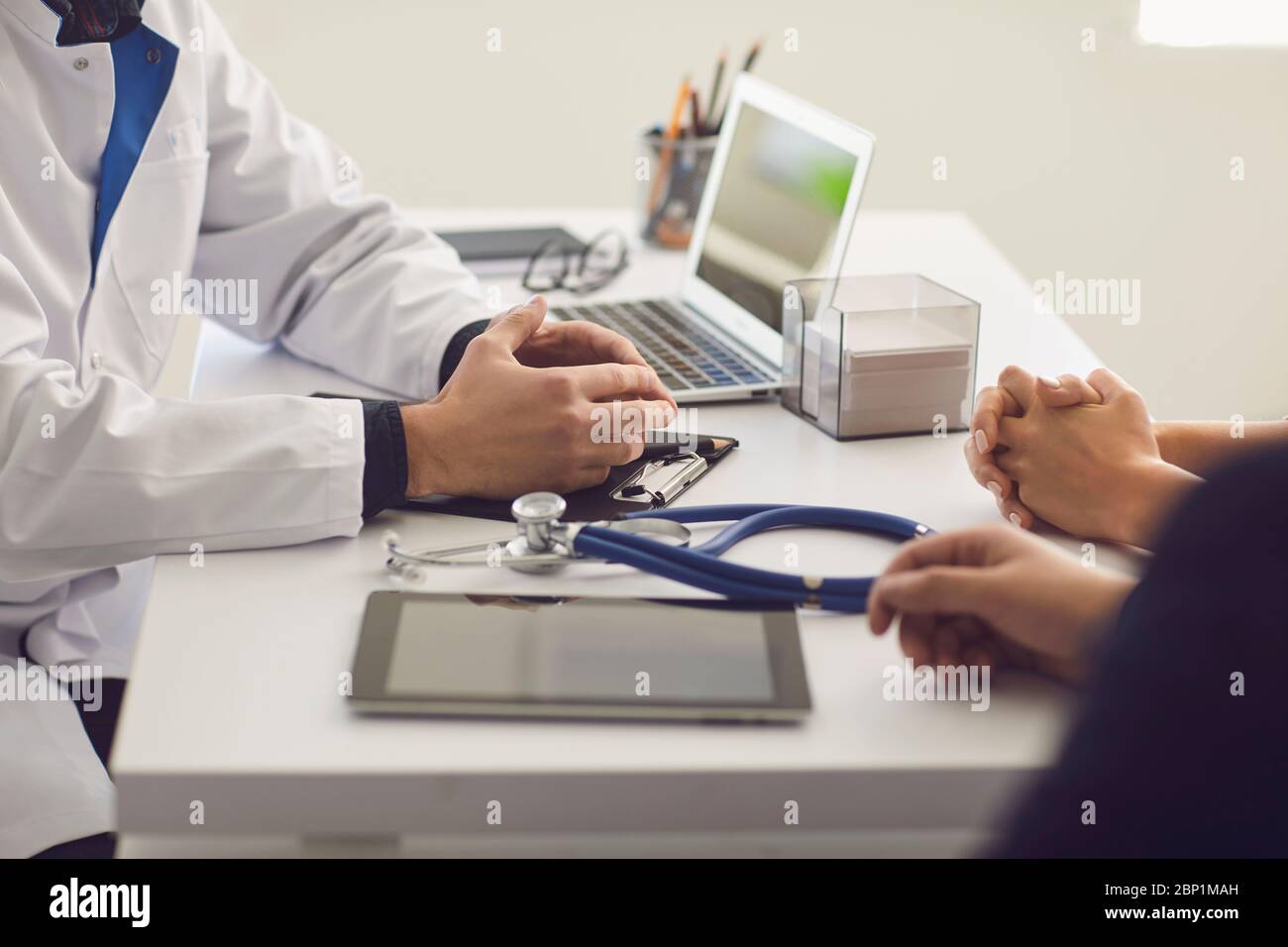 Confident doctor and couple patient sitting at the table in clinic ...
