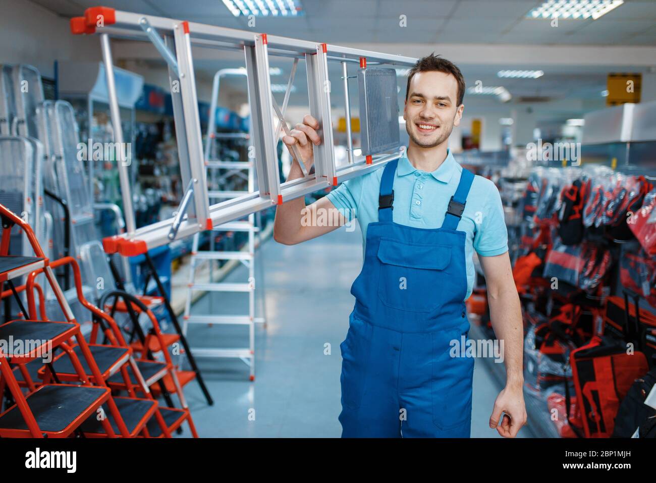 Worker holds aluminum stepladders in tool store Stock Photo - Alamy