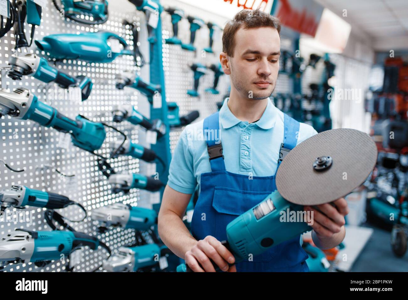 Male worker holds angle grinder in tool store Stock Photo - Alamy