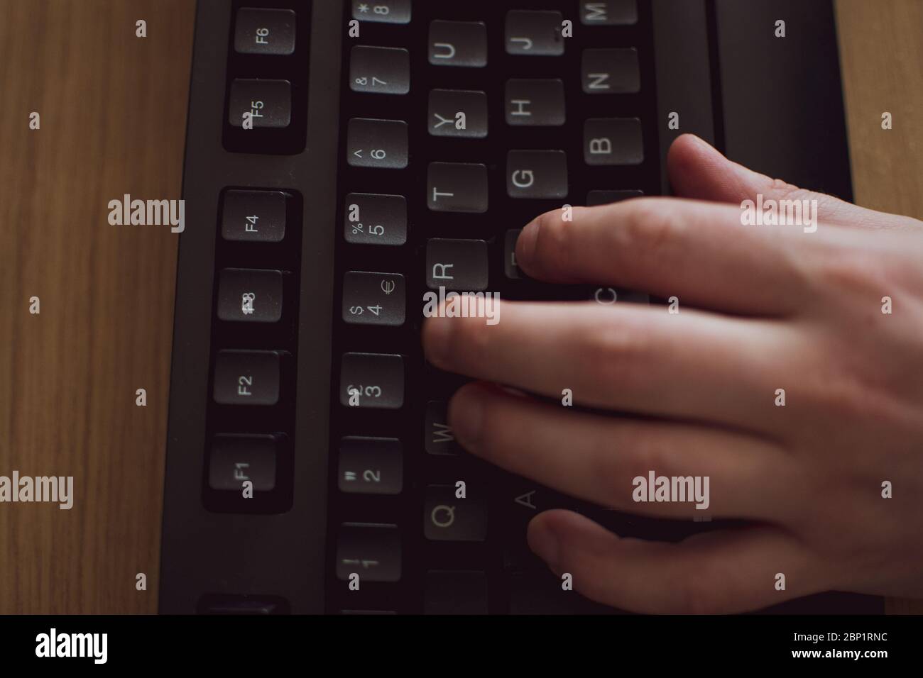 Top down of a hand typing on a black key board on a wooden desk Stock ...