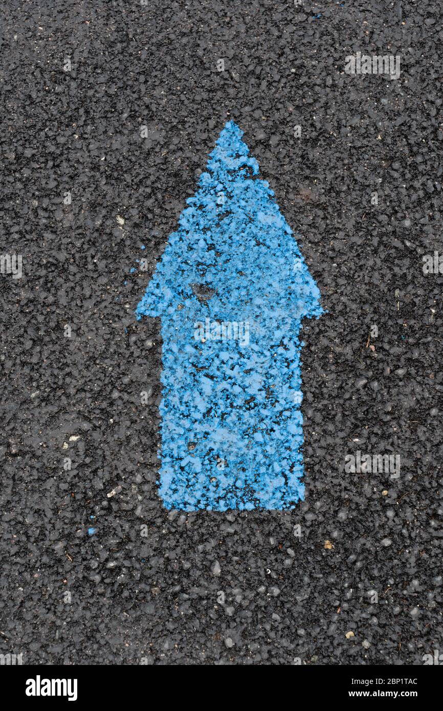 Blue arrow on black asphalt road forward direction sign background ...