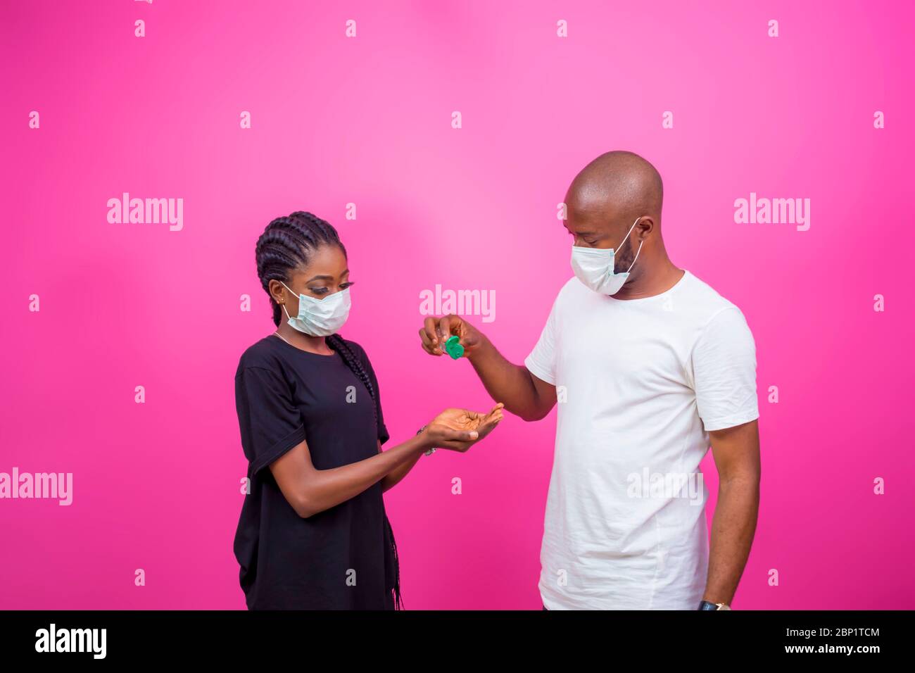 young black man giving hand sanitizer to a beautiful lady to keep her ...