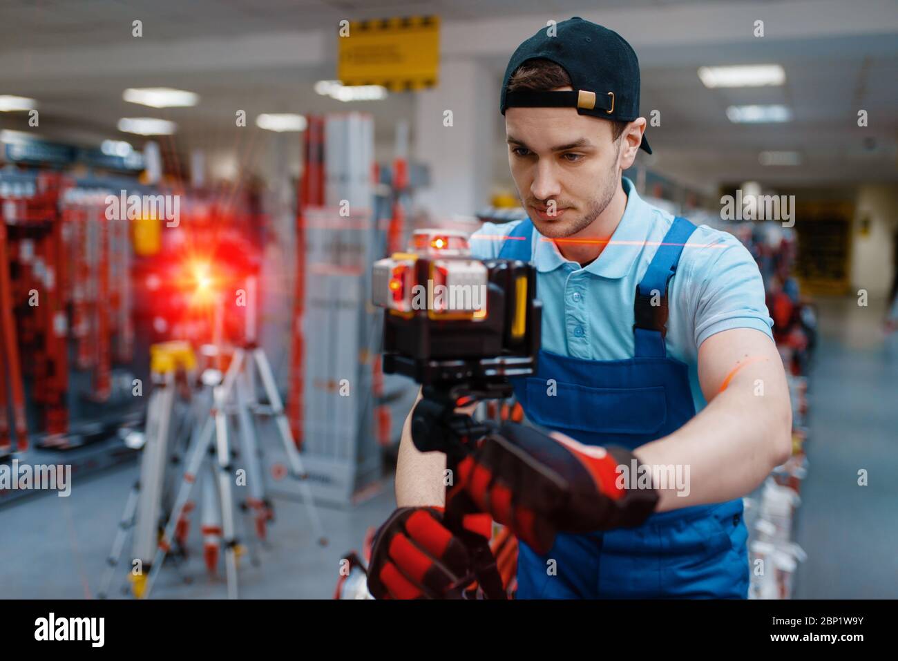 Worker testing laser level on tripod in tool store Stock Photo - Alamy
