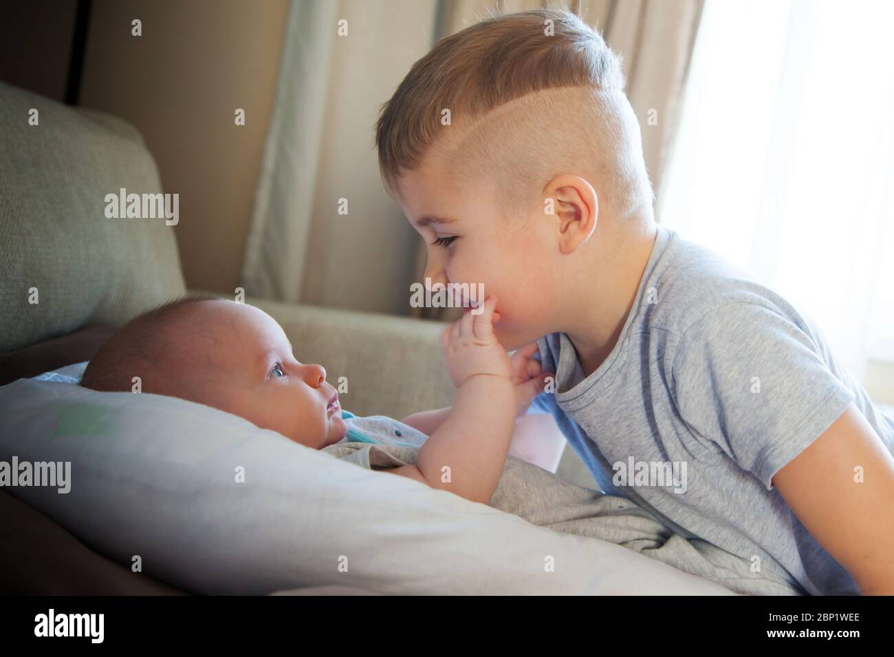 Two brothers older and younger on the couch. Newborn baby and boy of ...